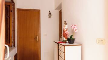 Um corredor com uma porta de madeira, um armário branco e um aparelho de ar condicionado na parede.