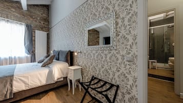 Quarto com cama, mesa de cabeceira, espelho e vista para o banheiro.