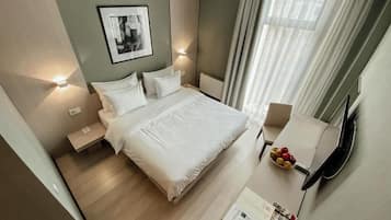 Quarto de hotel com uma cama, mesas de cabeceira, televisão de tela plana e uma cesta de frutas.