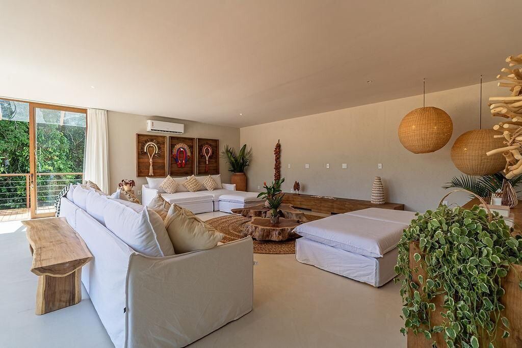 Uma sala de estar moderna com um sofá seccional, uma mesa de centro de madeira e uma janela grande com vista para o verde.