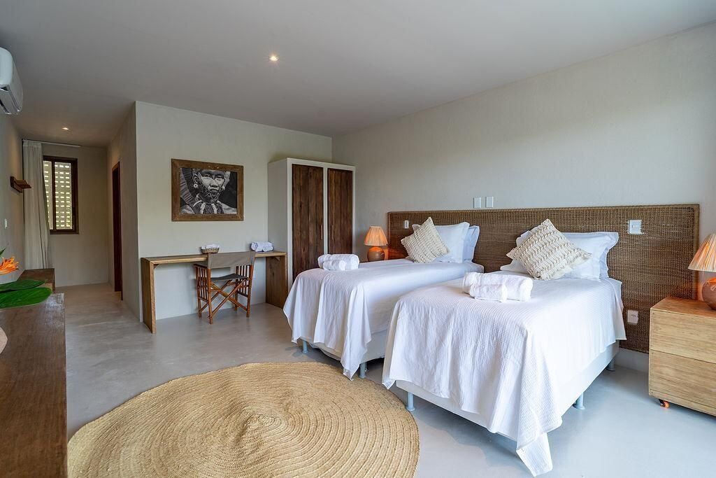 Quarto com duas camas, uma escrivaninha e uma cadeira.