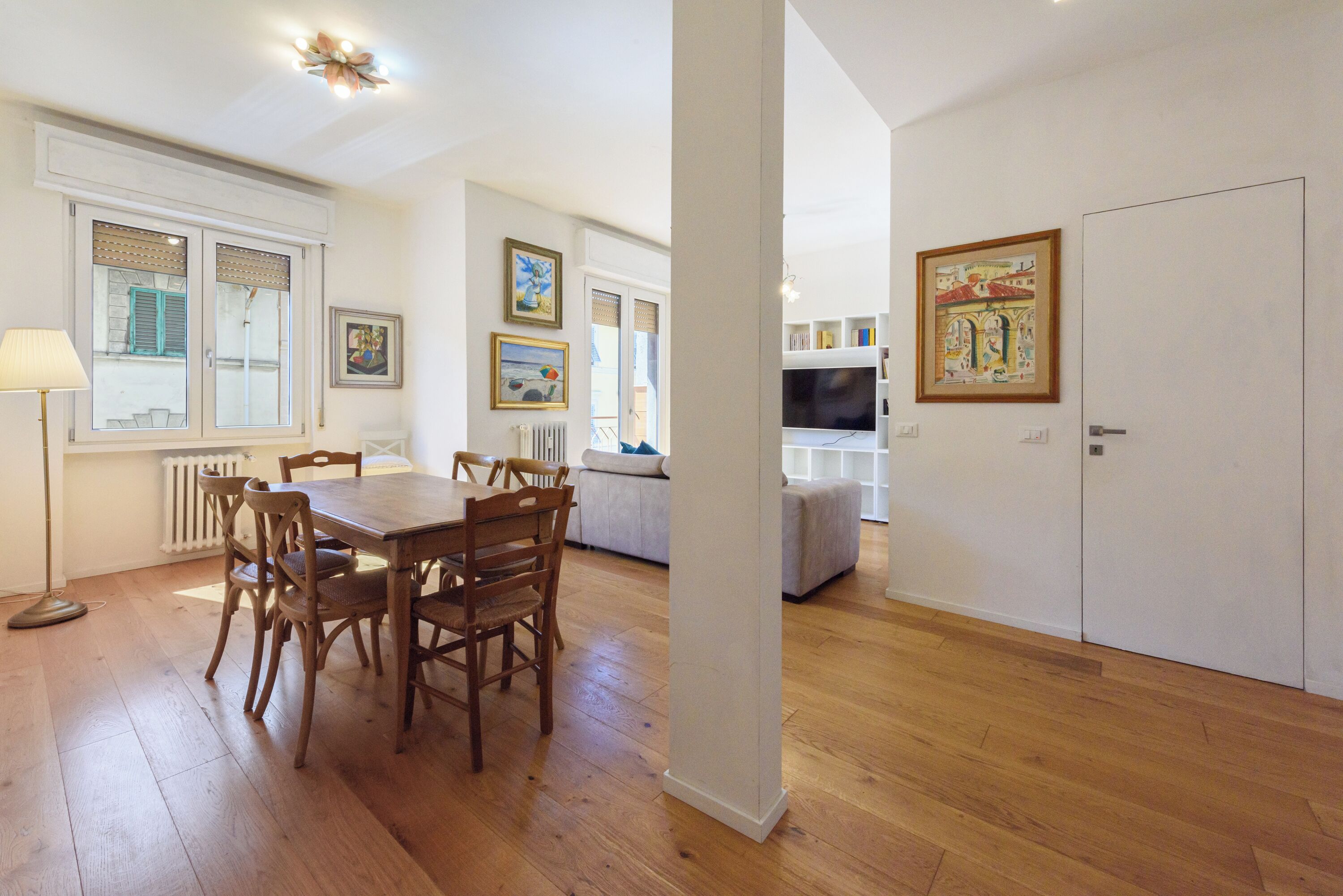 A spacious living area with a dining table, chairs, a sofa, and a television.