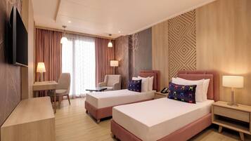 Quarto de hotel com duas camas, uma escrivaninha, uma cadeira, uma televisão e um abajur.