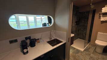 Uma casa de banho moderna com chuveiro, sanita e lavatório.
