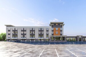 Um hotel moderno com design contemporâneo, teto plano, várias janelas e um estacionamento à frente.