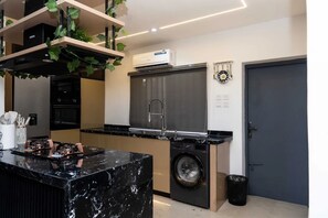 Cozinha moderna com máquina de lavar embutida, pia e fogão.