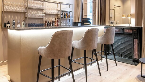 Uma área de bar com balcão, banquetas e uma adega com garrafas.