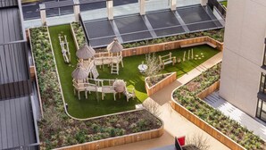 Um jardim no terraço com brinquedos, áreas de estar e vasos de plantas.
