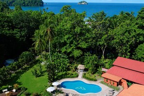 Um resort tropical com piscina, cercado por vegetação exuberante e vista para o oceano.
