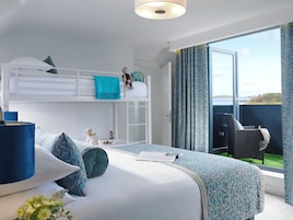 Quarto de hotel com beliche, varanda e área de estar com mesa.