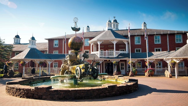 A historic building with a central fountain, a covered porch, and a clear blue sky.