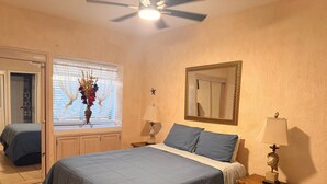 Quarto com cama, luminárias de cabeceira, um espelho e uma janela com cortinas.