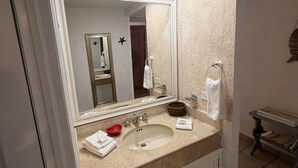 Casa de banho com um espelho grande, uma pia e um porta-toalhas.