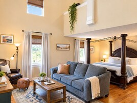 Quarto com cama de dossel, sofá, mesa de centro e vista para o exterior.