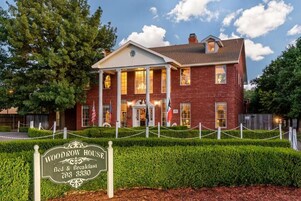 Um grande edifício de tijolos com uma placa que diz 'Woodrow House Bed & Breakfast' e um número de telefone.