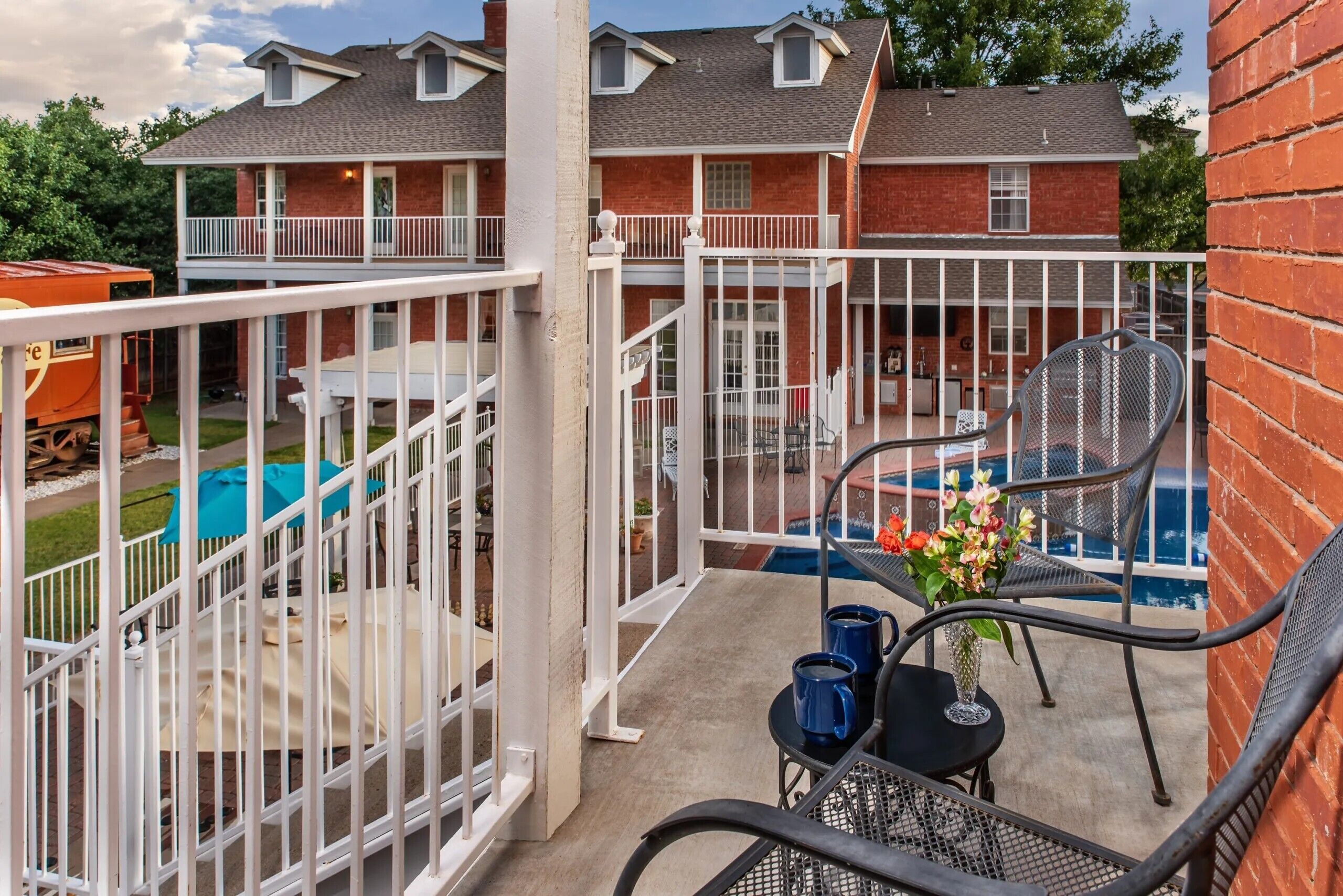 A balcony with a pool, outdoor furniture, and a view of a two-story house.