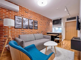 Uma sala de estar moderna com uma parede de tijolos, um sofá, uma mesa de centro e uma televisão.