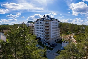 Um hotel com vários andares e um pátio central, rodeado por árvores.