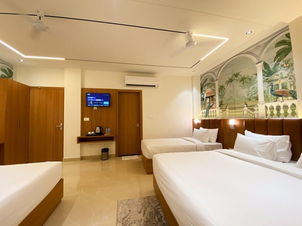 Quarto de hotel com duas camas, uma televisão, uma escrivaninha e um mural na parede.