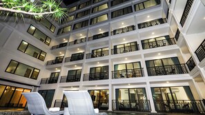 Hotel com vários andares, varandas, área de estar externa e fachada bem iluminada.