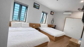 Quarto de hotel com duas camas, um guarda-roupa e uma janela com vista.