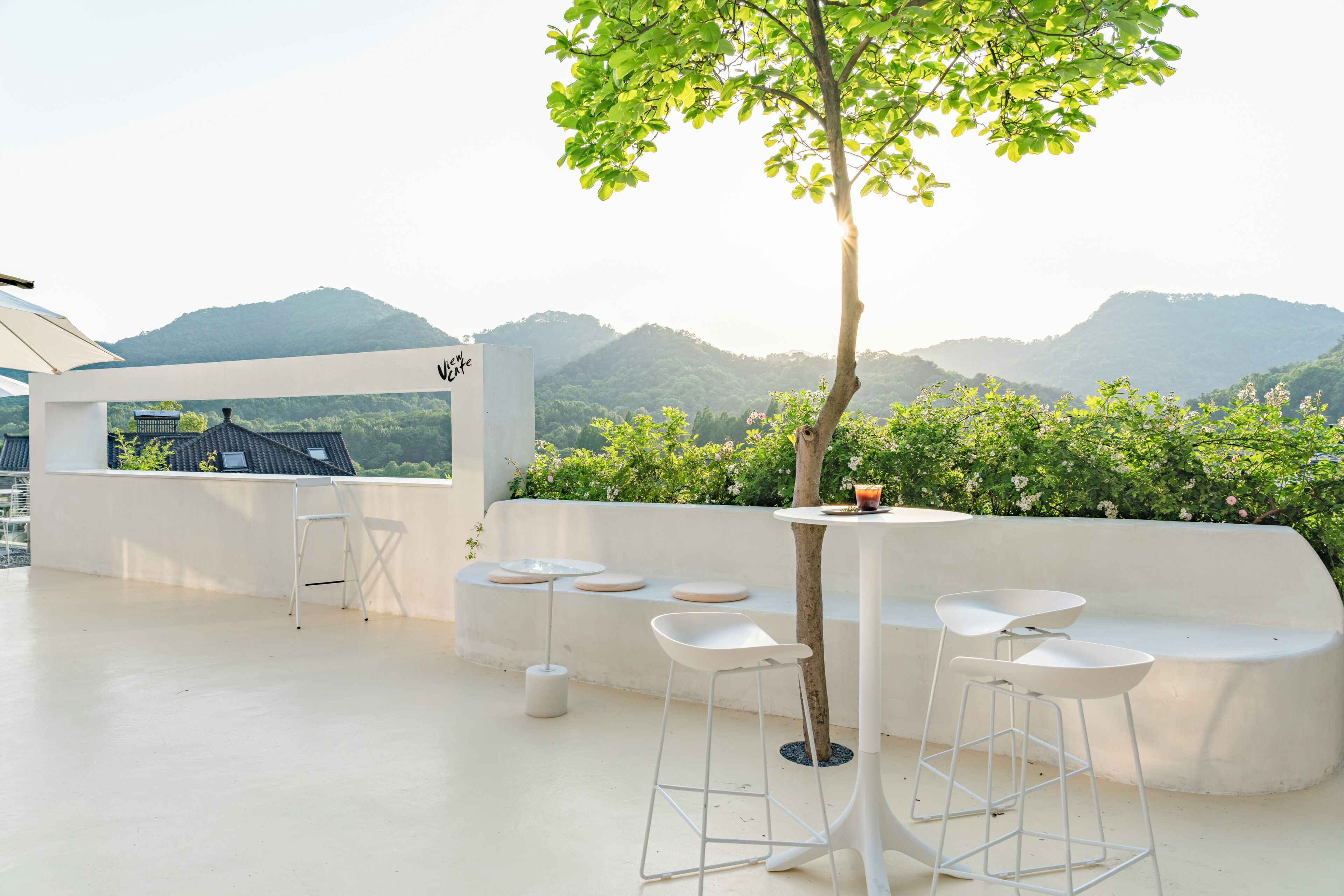 Um terraço no telhado com área de estar, uma árvore e vista para as montanhas.
