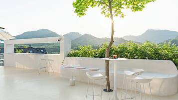 Um terraço no telhado com área de estar, uma árvore e vista para as montanhas.
