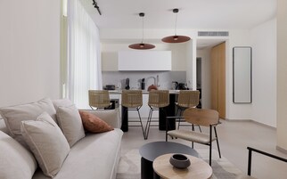 Uma sala de estar moderna com sofá, mesa de centro e área de jantar com cadeiras.