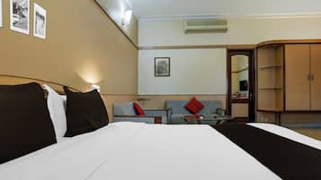 Quarto de hotel com uma cama grande, uma escrivaninha com cadeira, um sofá e um guarda-roupa.