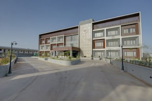 Um hotel moderno com um pátio central, várias varandas e uma combinação de painéis de concreto e madeira.