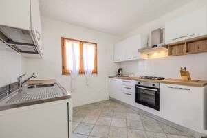 Uma cozinha compacta com fogão a gás, forno e pia de aço inoxidável.