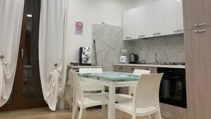Uma cozinha moderna com armários brancos, uma mesa de jantar de vidro e um forno embutido.