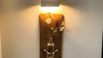 Uma luminária fixada na parede com um vaso de flores.