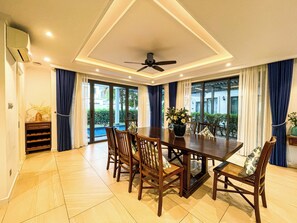 Uma sala de jantar com uma mesa grande, cadeiras e um ventilador de teto.