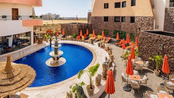 Uma área de piscina no terraço com uma fonte, rodeada por assentos externos e guarda-sóis.