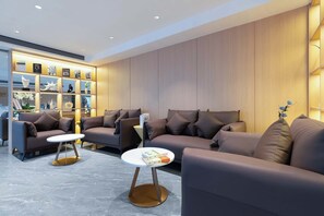 Uma sala de estar moderna com dois sofás, duas mesinhas de centro redondas e uma estante embutida com objetos decorativos.