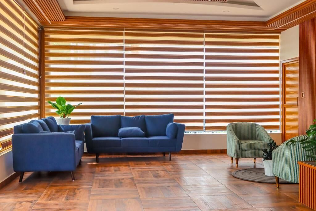 Uma sala de estar moderna com um sofá azul, uma poltrona verde e uma planta em vaso.