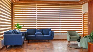 Uma sala de estar moderna com um sofá azul, uma poltrona verde e uma planta em vaso.