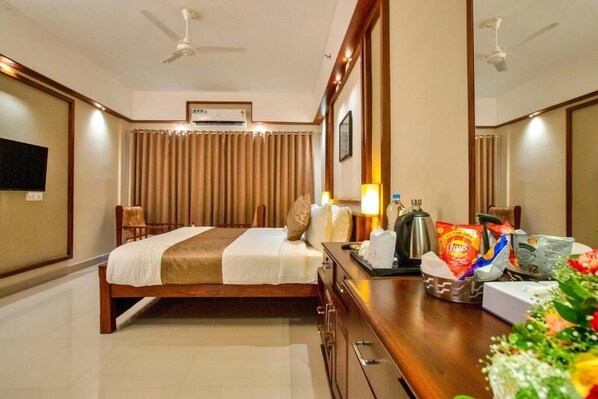 Quarto de hotel com cama, mesa de cabeceira, luminária, ar-condicionado e espelho.