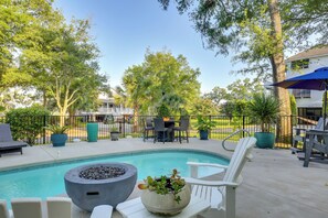 Uma área junto à piscina com lareira, espreguiçadeiras e conjunto de jantar.