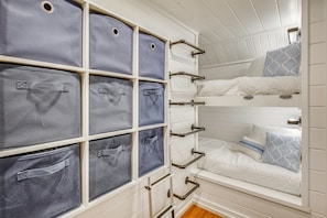 Quarto com beliches e armários com portas de tecido.