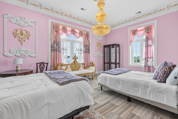 Quarto com duas camas, um candelabro e decorações elaboradas nas paredes.