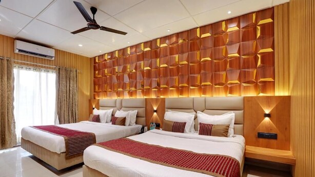 A hotel room with two beds, a ceiling fan, an air conditioning unit, and a decorative wall panel.