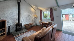 Uma sala de estar acolhedora com lareira, um sofá, uma mesa com cadeiras e vista para o exterior.