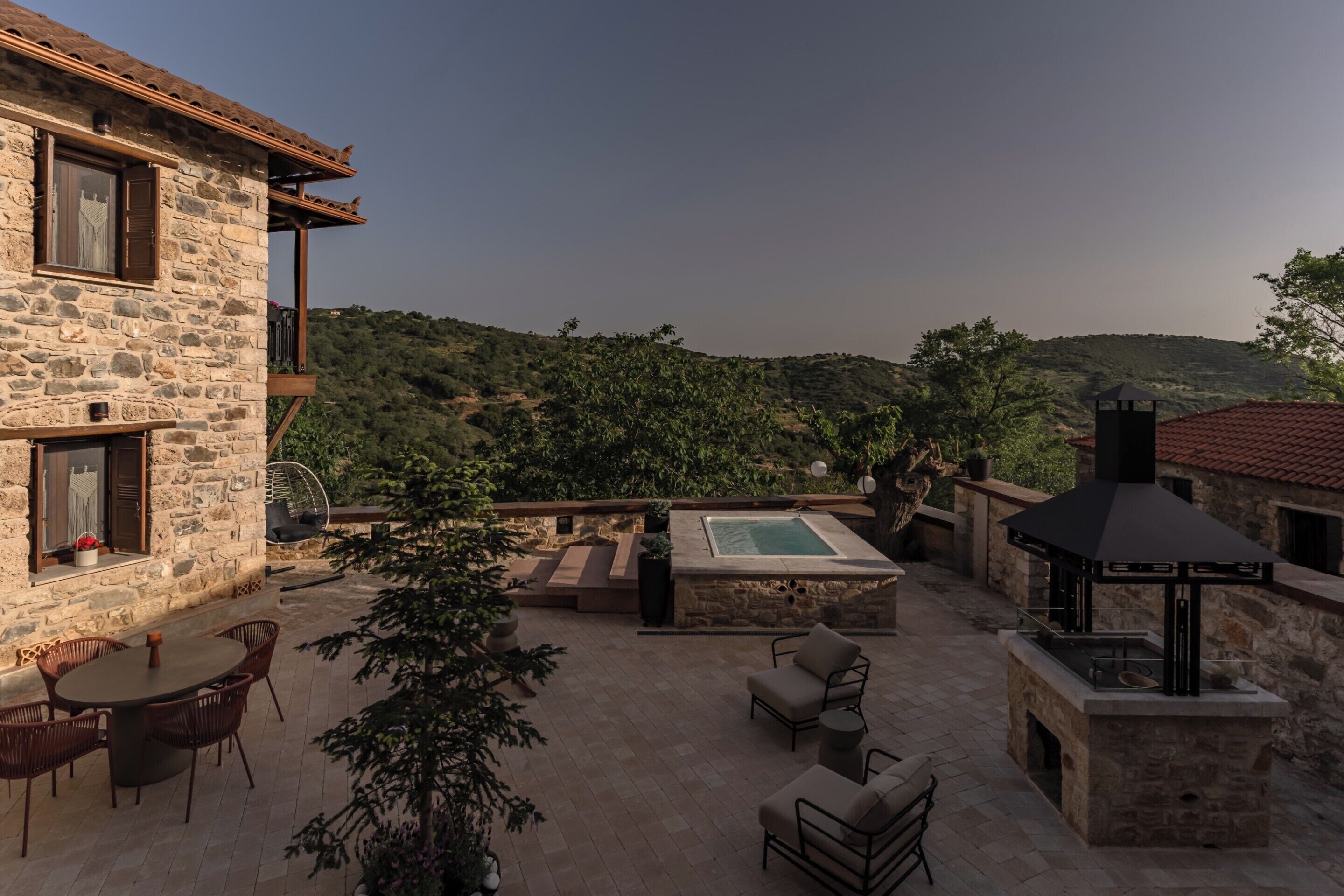 Um edifício de pedra com piscina, área de estar ao ar livre e vista para o campo.