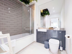Uma casa de banho moderna com chuveiro em cabine de vidro, lavatório branco e sanita.