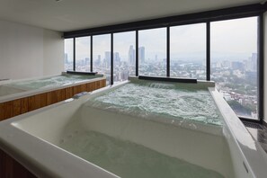 Quarto com duas banheiras de hidromassagem e vista para a cidade.