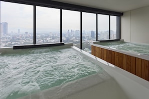 Quarto com duas banheiras de hidromassagem e vista para a cidade.