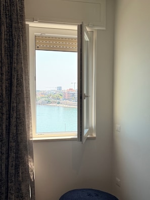 Quarto com janela que oferece vista para a água e para o horizonte da cidade.