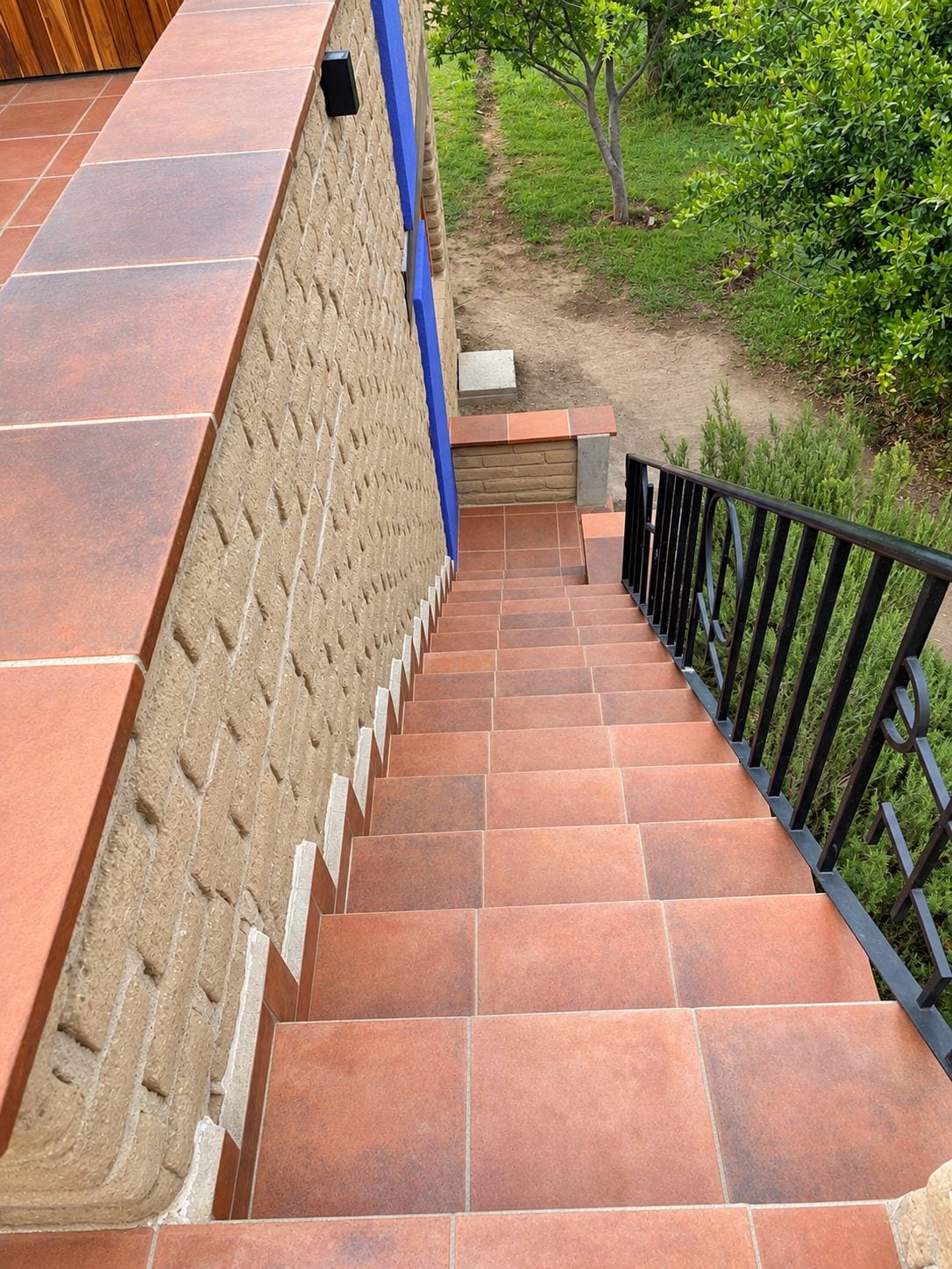 Escadaria com ladrilhos vermelhos que dá acesso a um deck de madeira.